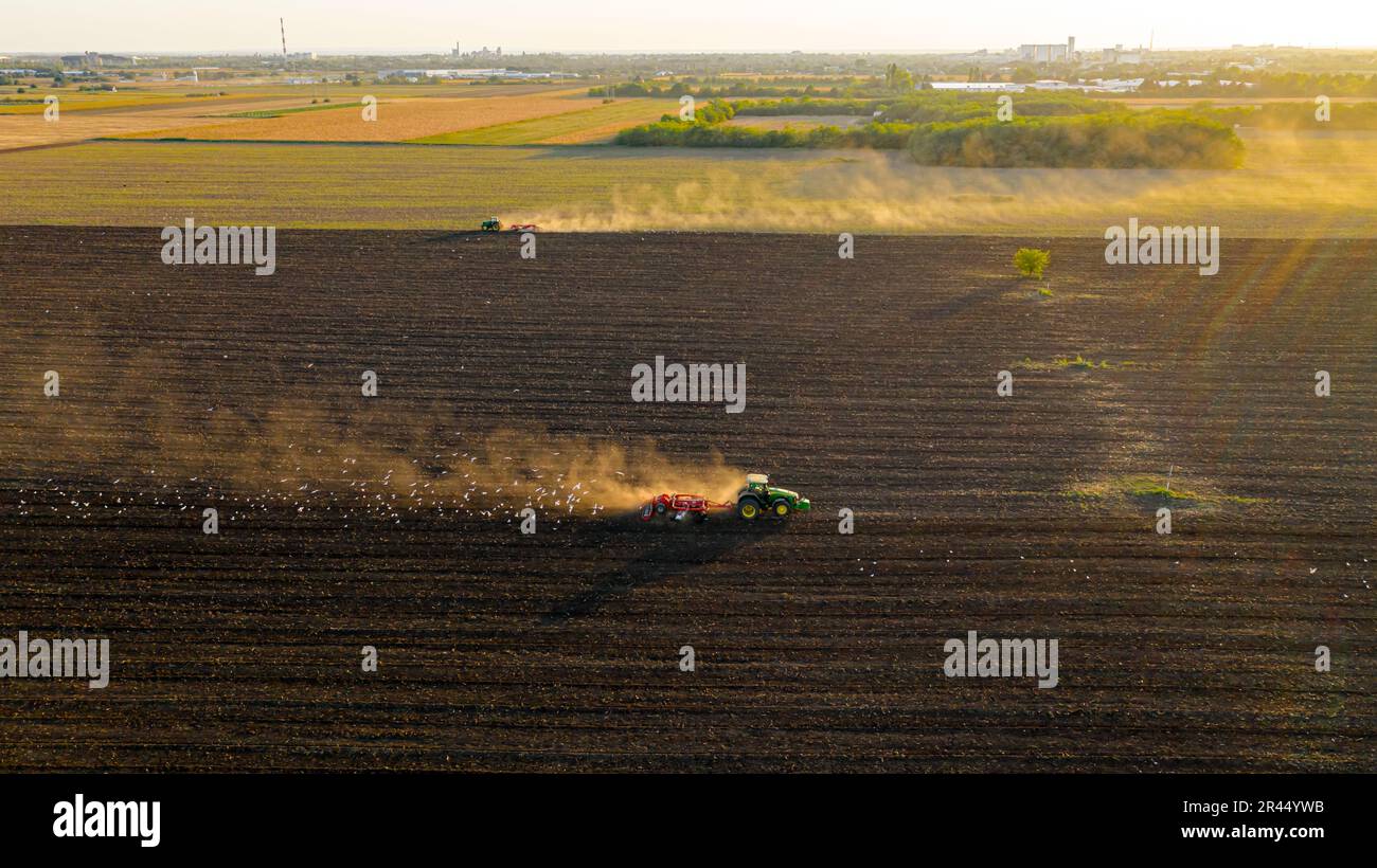 Above view with backlight, tractor pull disc harrow, harrowing farmland ...
