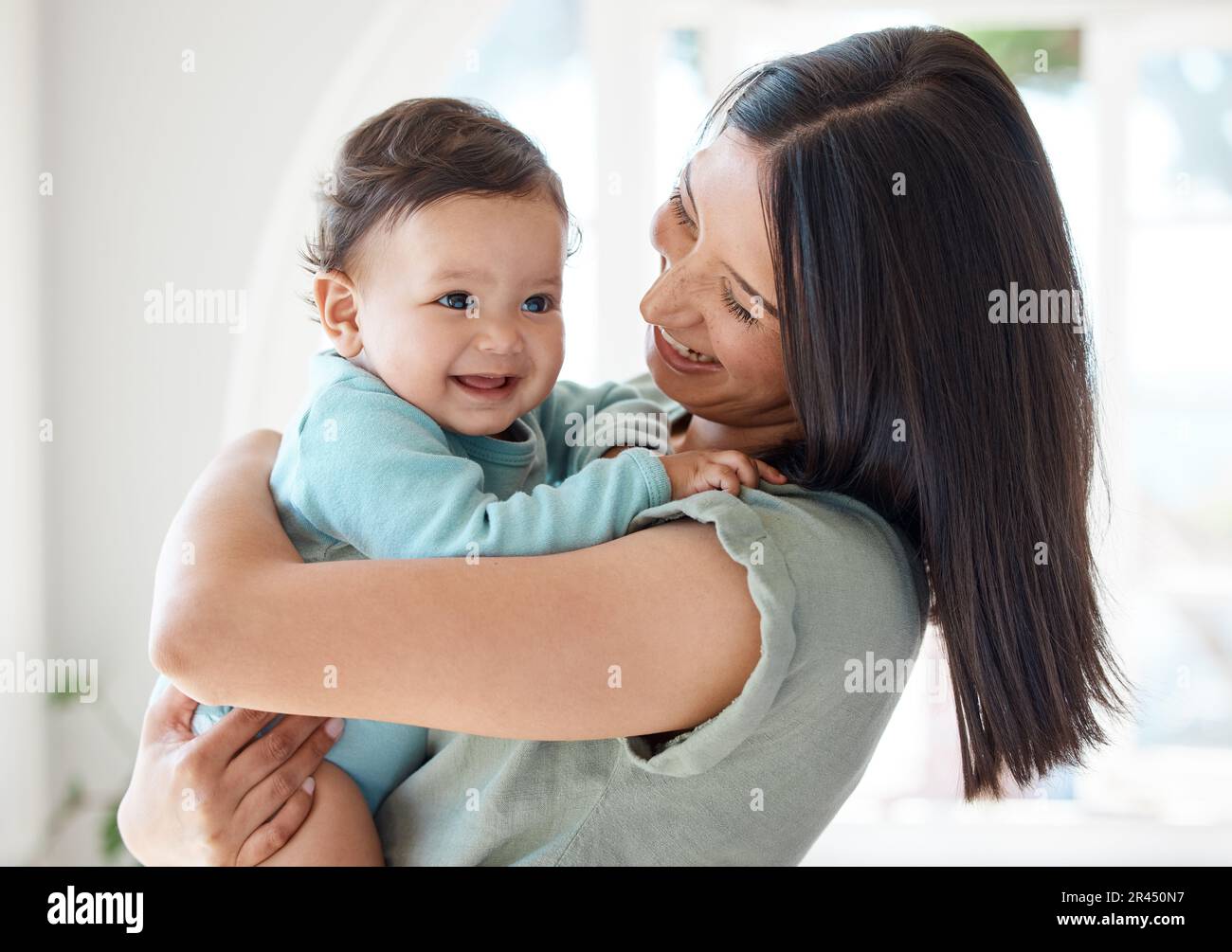 Mother holding happy baby in home for love, care and quality time ...