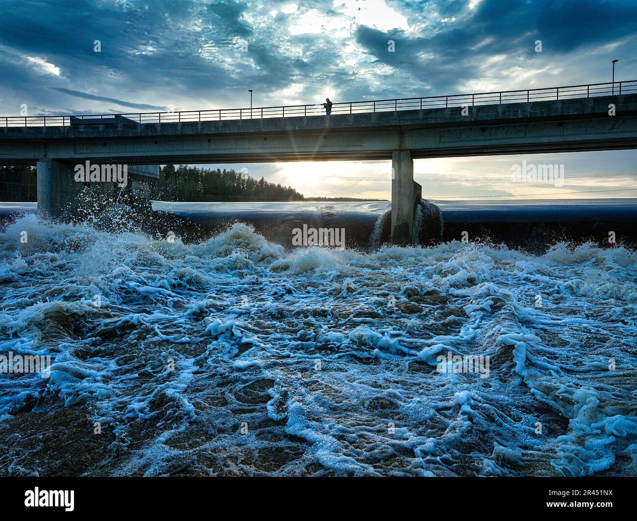 A scenic view of a bridge spanning a river with rippling waves below ...