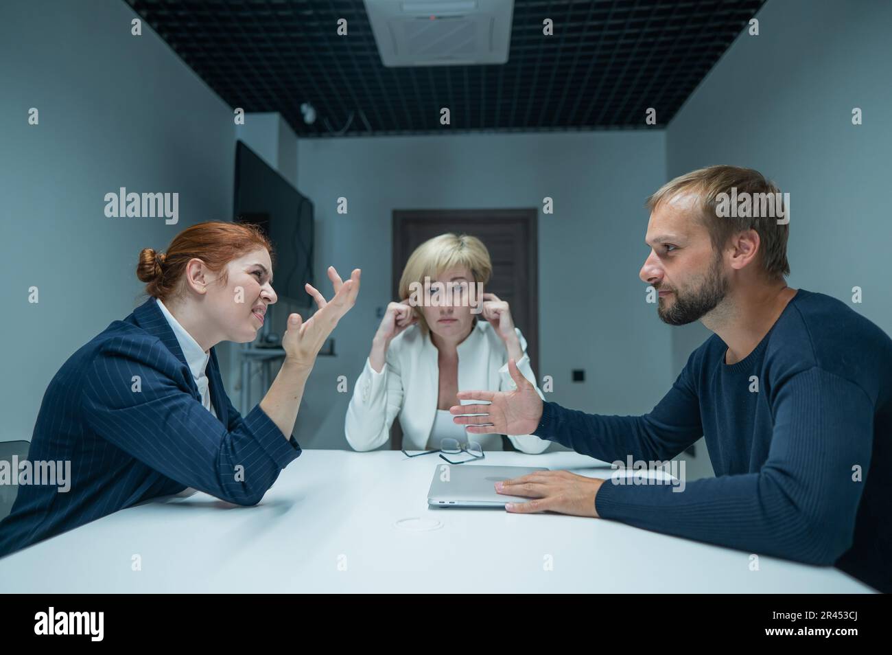 Blond, red-haired woman and bearded man in suits in the office ...