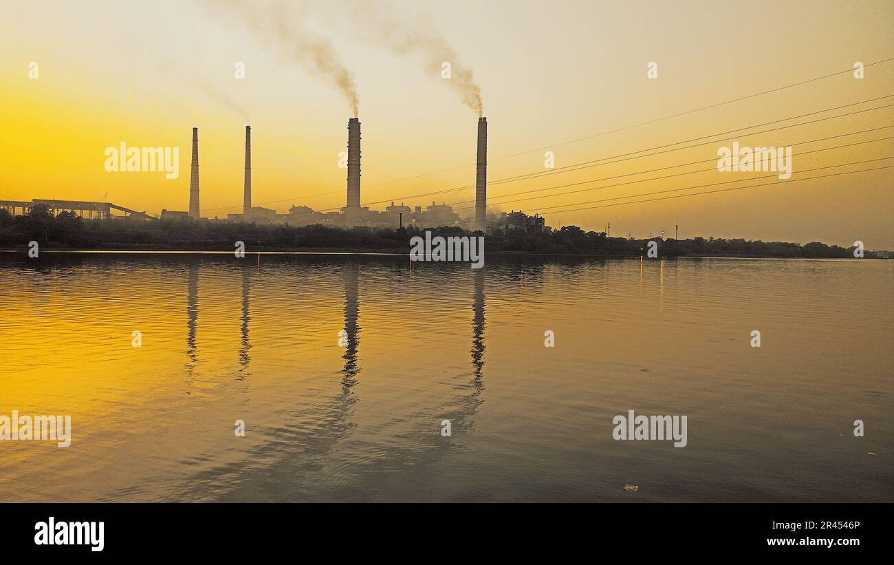 An industrial factory complex reflecting on Chambal river at golden ...