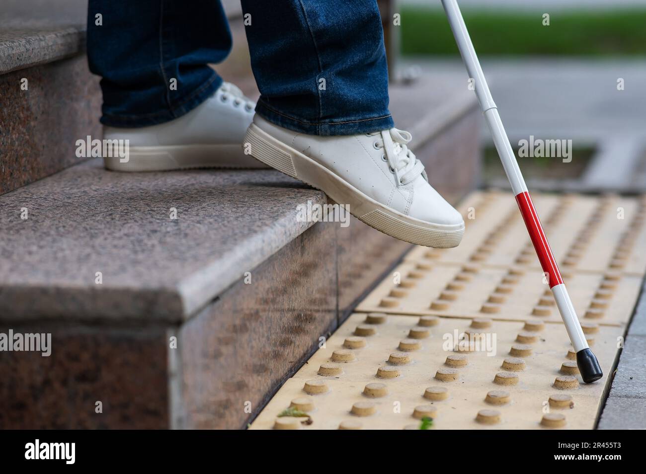 Close-up of female foot, walking stick and tactile tiles. Blind woman ...