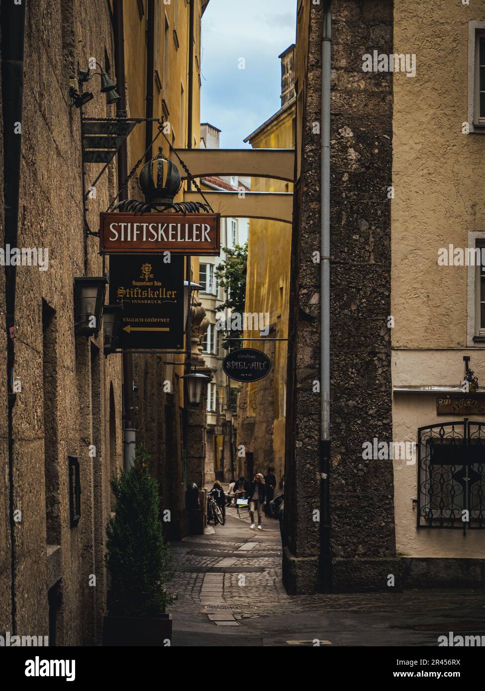 Medieval narrow street alley with inn signs and people moody cloudy ...
