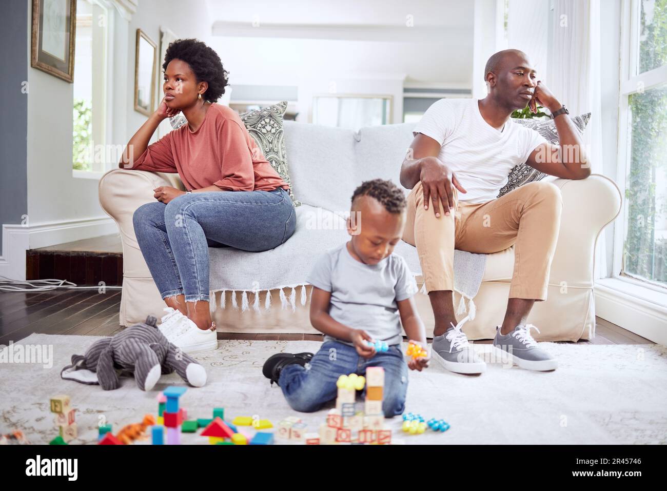 Family, fight and couple argue on a sofa, stress and divorce with playing child on a living room ...