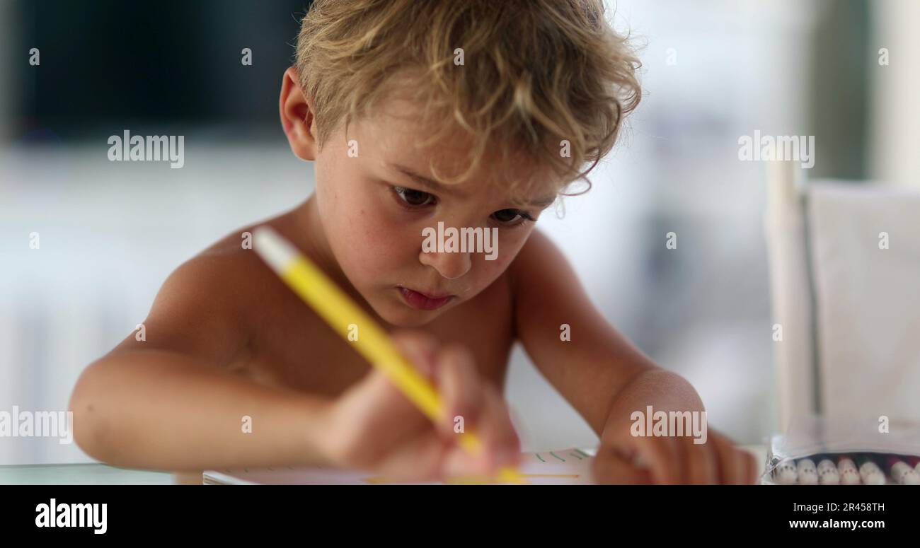 Artistic kid drawing on paper with yellow color pen. Focused ...
