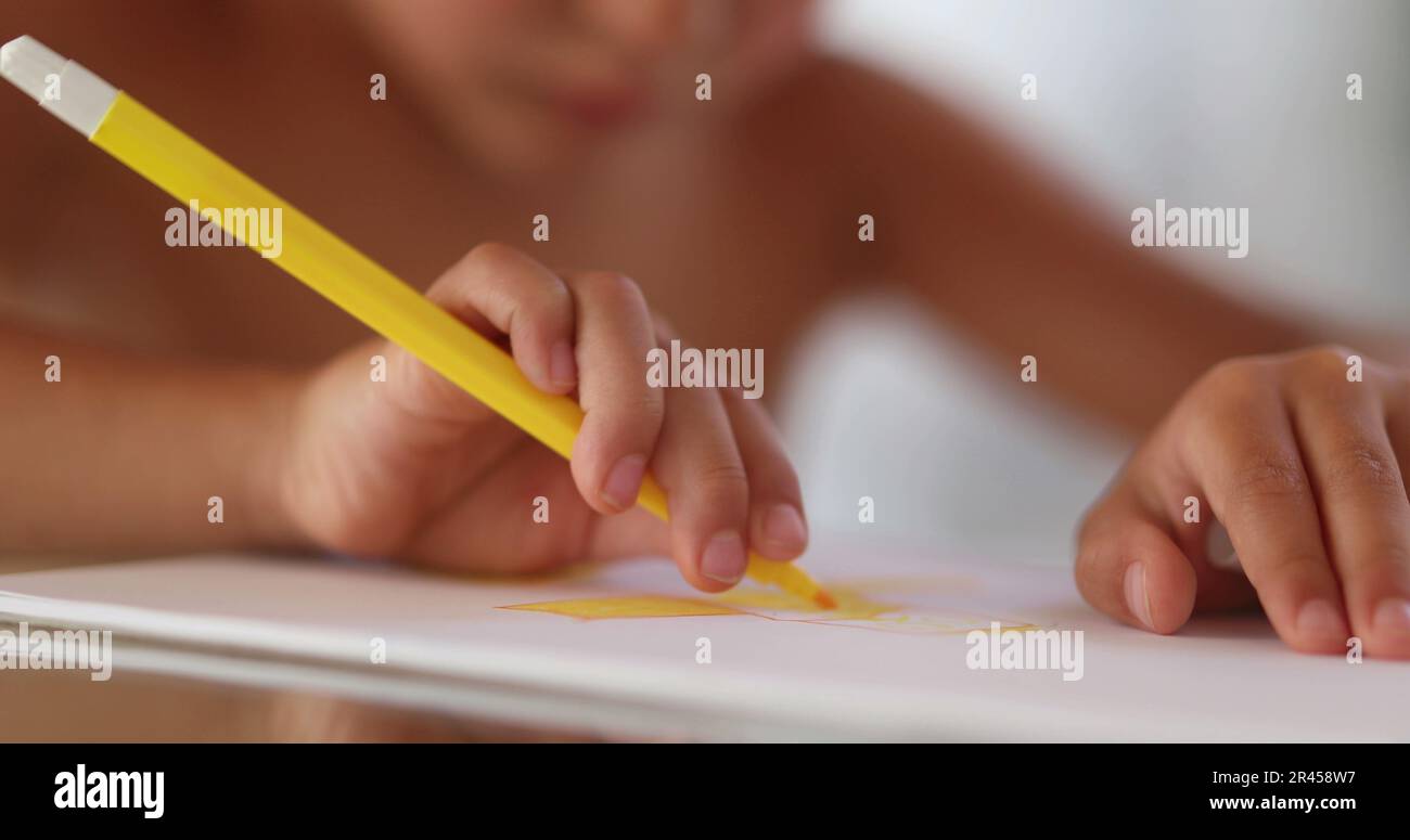 Artistic kid drawing on paper with yellow color pen. Focused ...