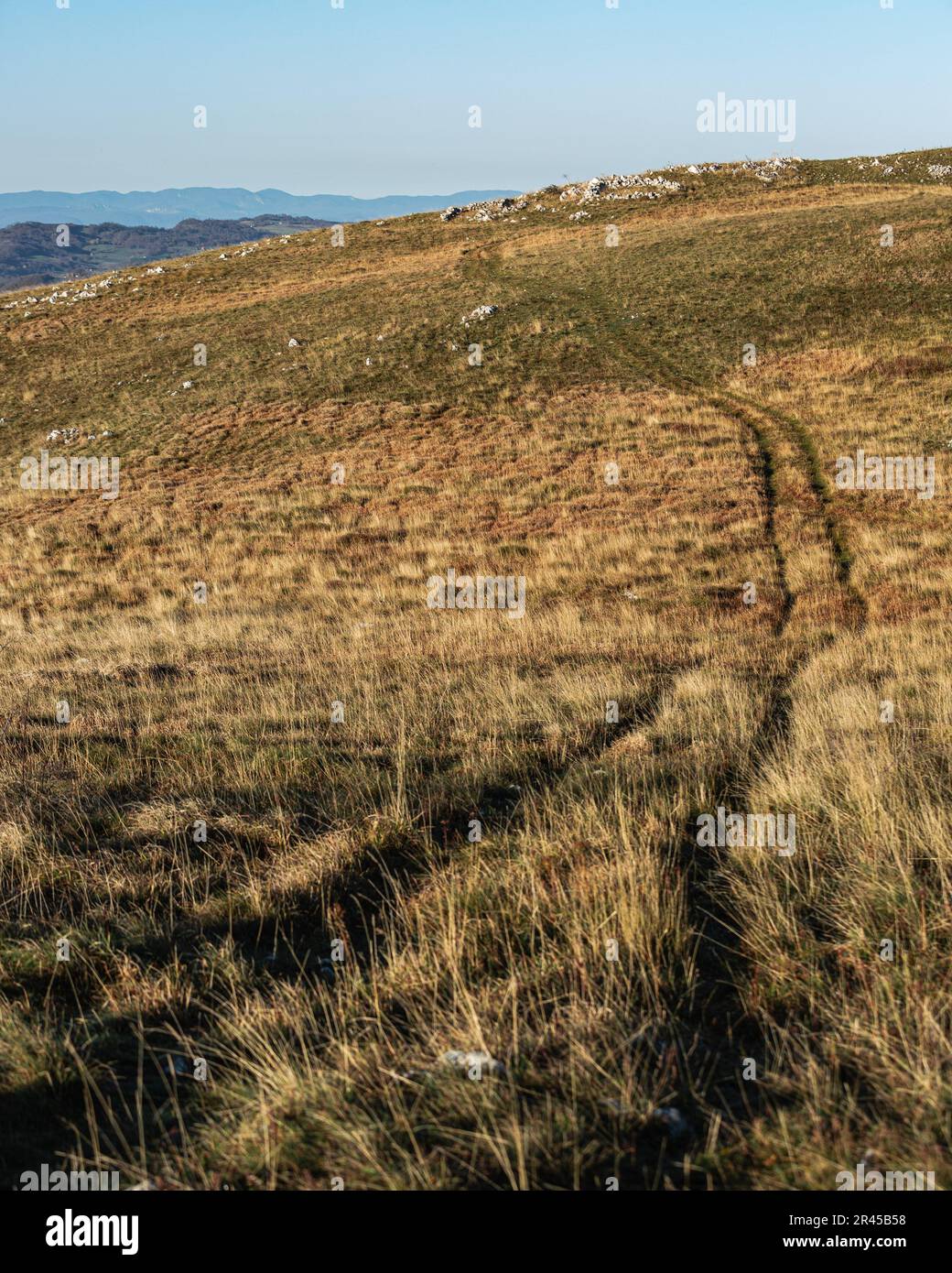 A vertical shot of a winding road cutting through a vast landscape of ...
