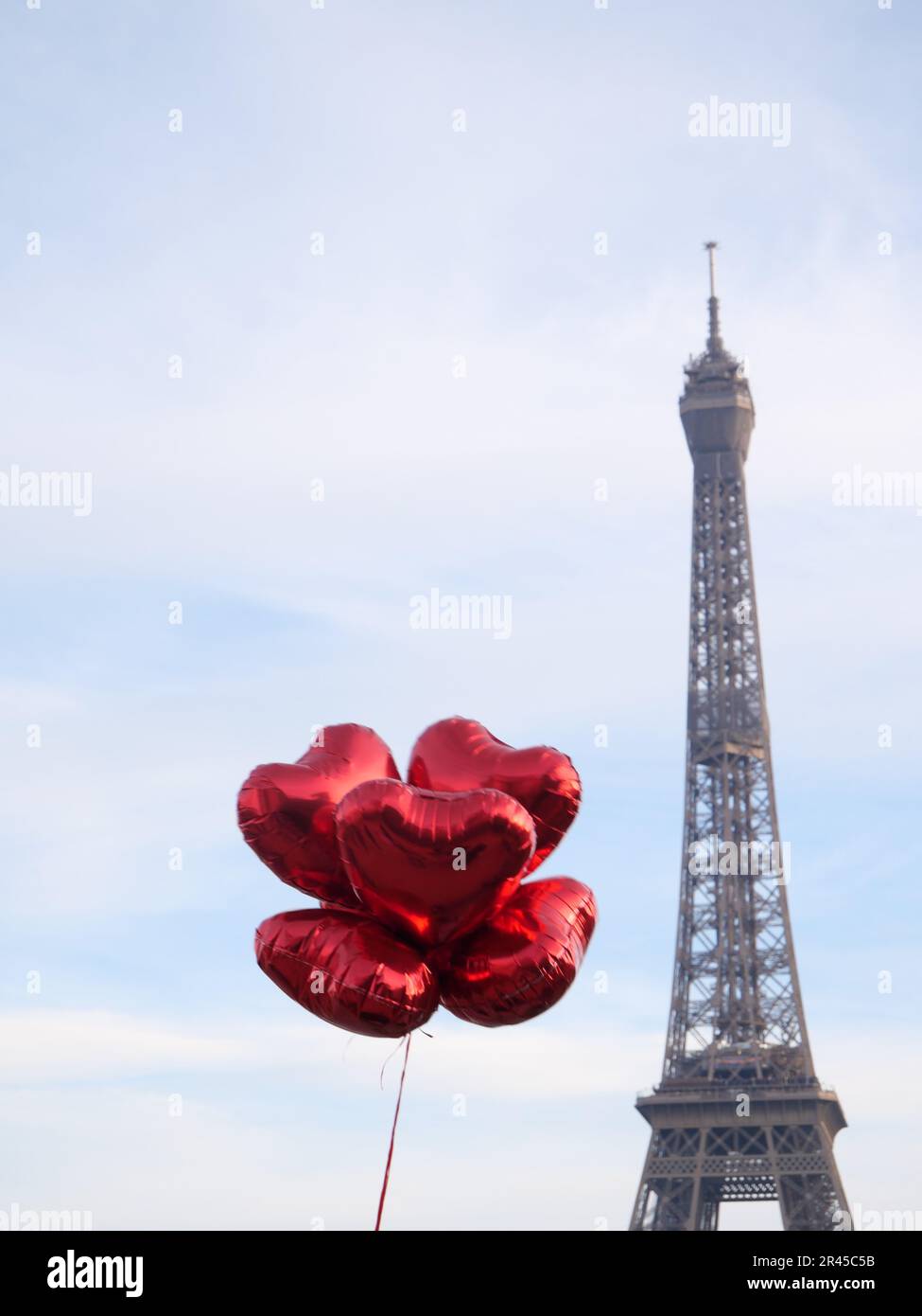 A vertical shot of heart-shaped balloons in front of the Eiffel Tower ...