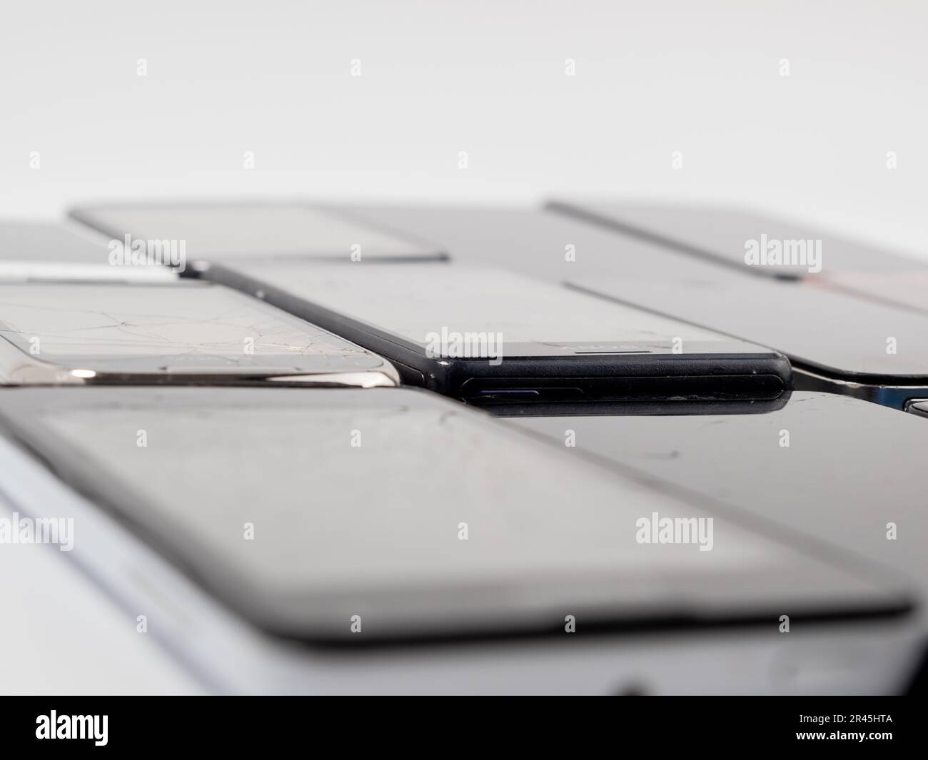 Damaged mobile phones. A bunch of broken smartphones. Used phones on a ...