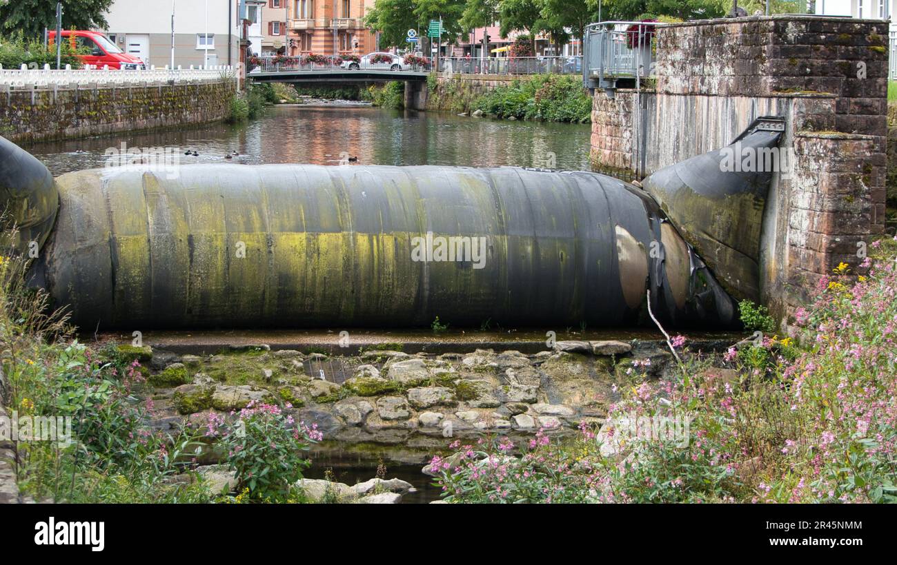 An industrial pipe on the edge of a canal, the surface of the water ...