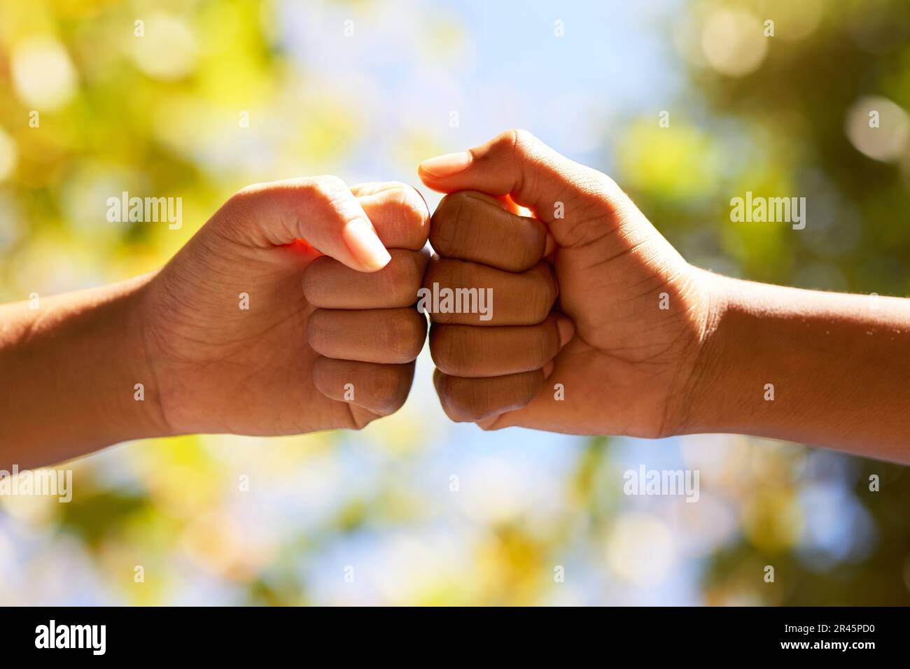 Two women give fist bump in nature, trees, support the planet Earth Day ...