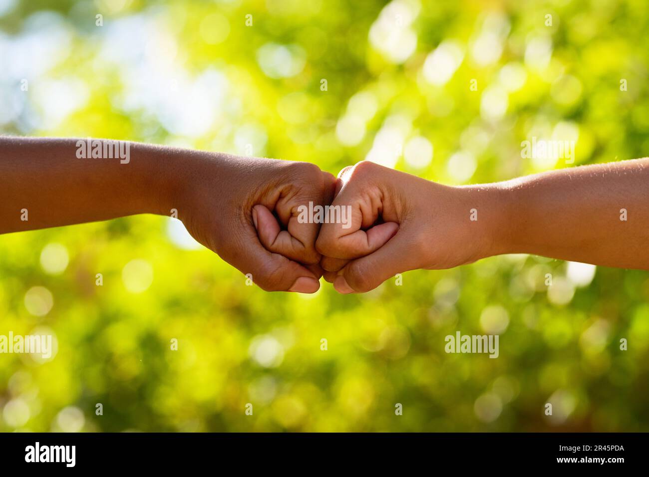 Two women give fist bump in nature, trees, support the planet Earth Day ...