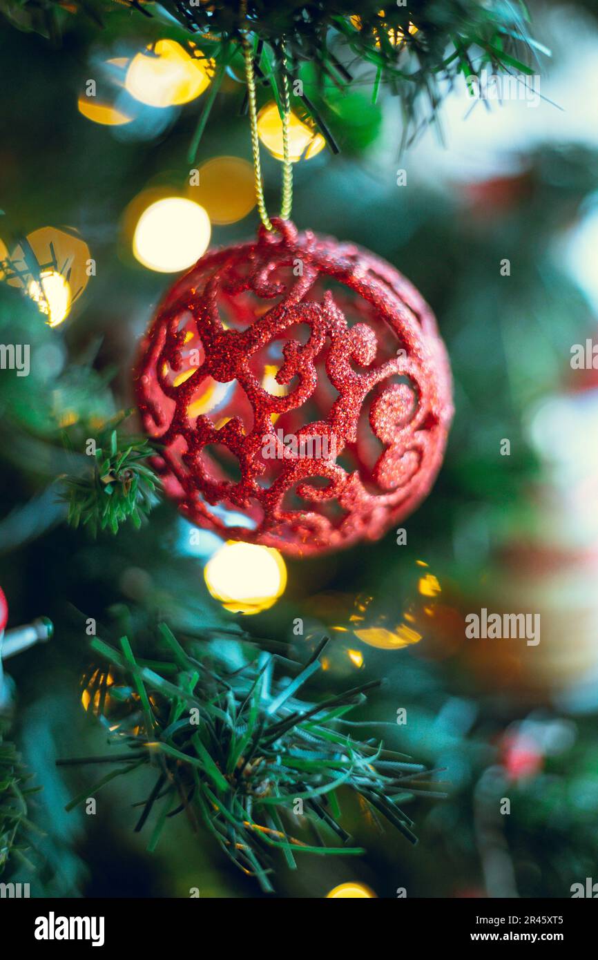 A close-up shot of a festive red ball toy hanging on a Christmas tree ...
