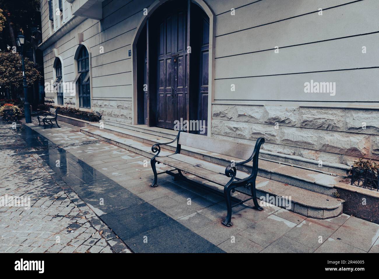 An outdoor bench in a courtyard in front of a white building Stock ...