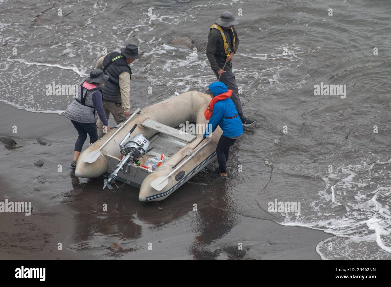 A group of older adults launching an inflatable boat into the water in ...