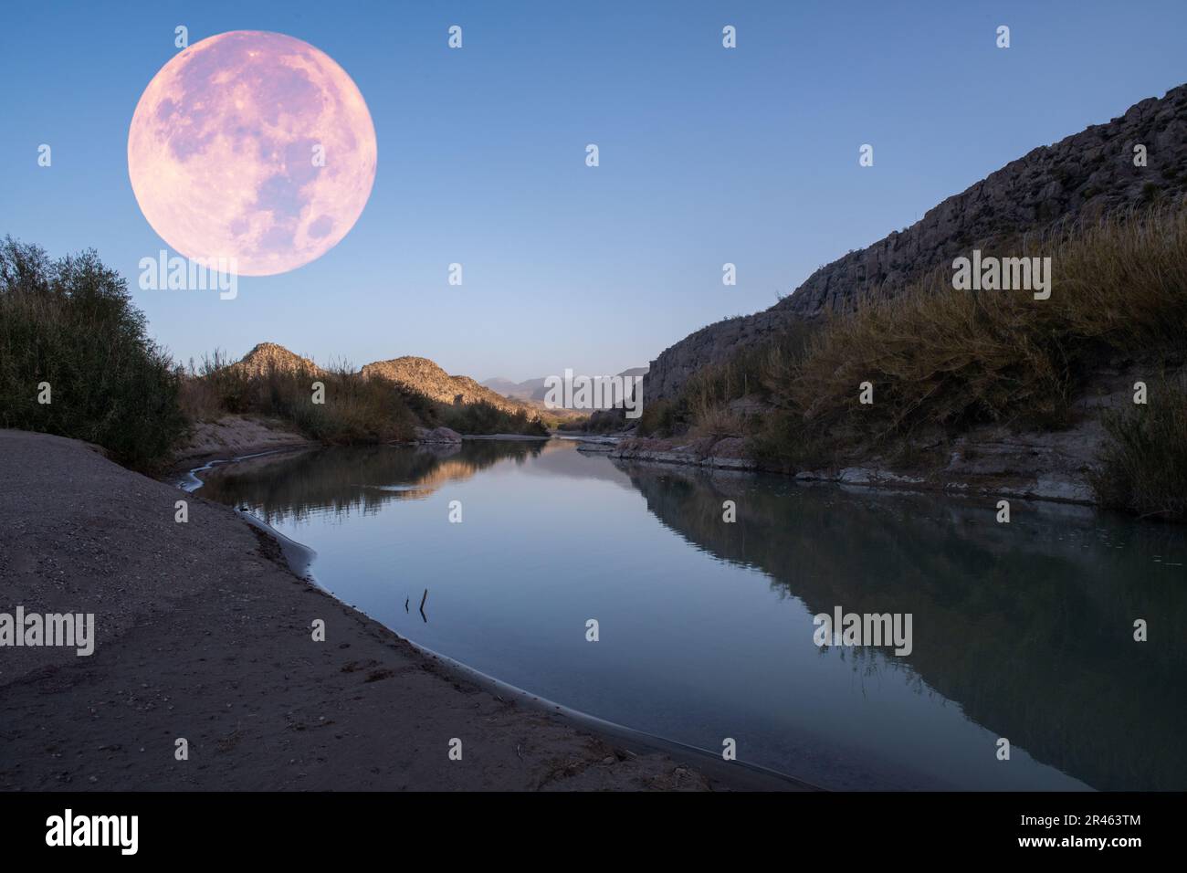 Giant orange moon over river in desert Stock Photo - Alamy