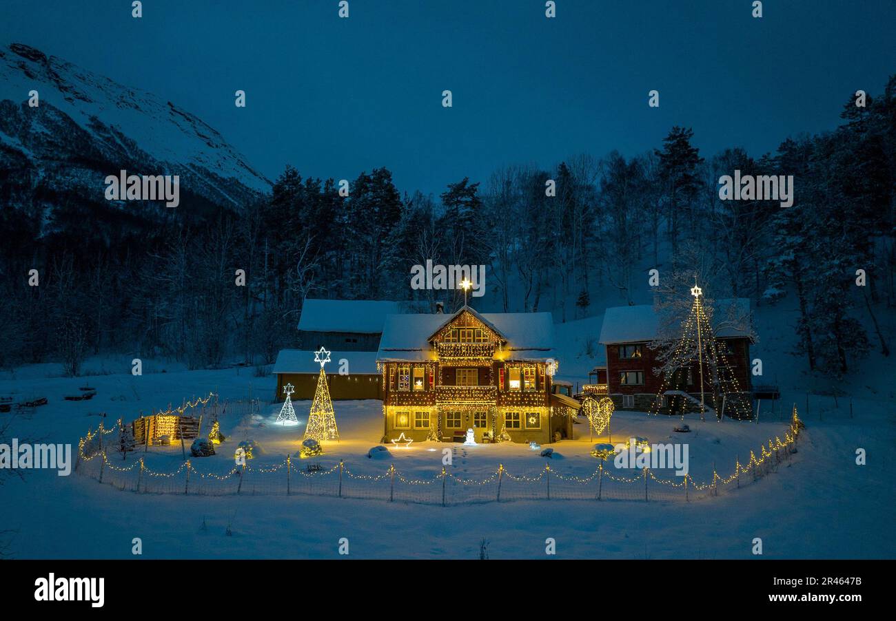 A traditional bright lit log cabin situated atop a snow covered ...