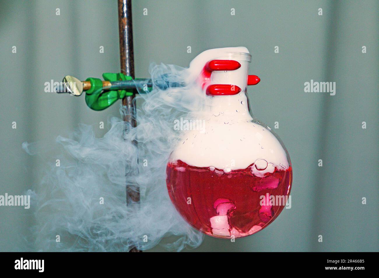 Red potion in glass dish smoking in laboratory during science ...