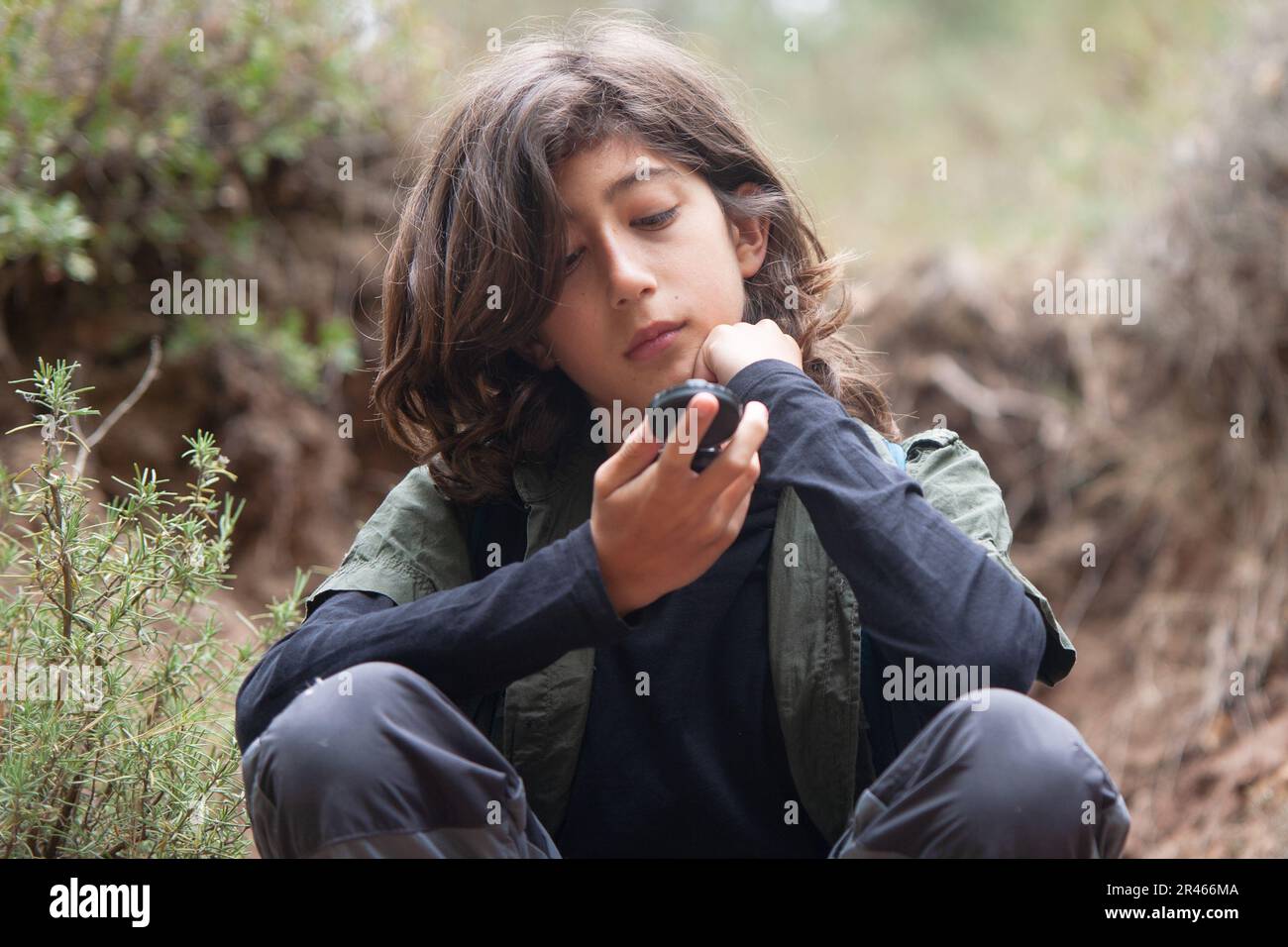 A child sits, passing the time, as they focus on the compass, engrossed ...