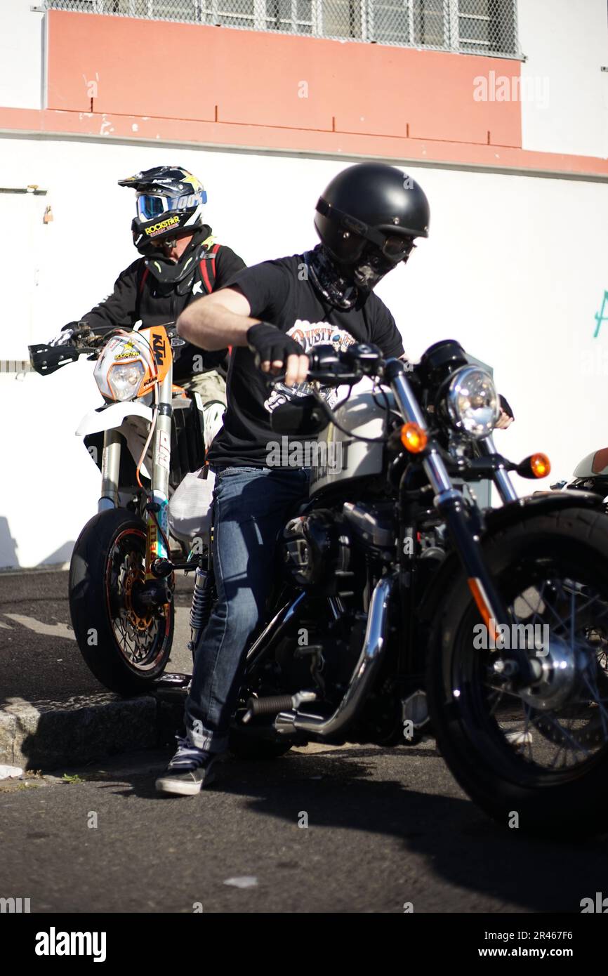 The two male motorcyclists wearing helmets are parked in a lot Stock ...