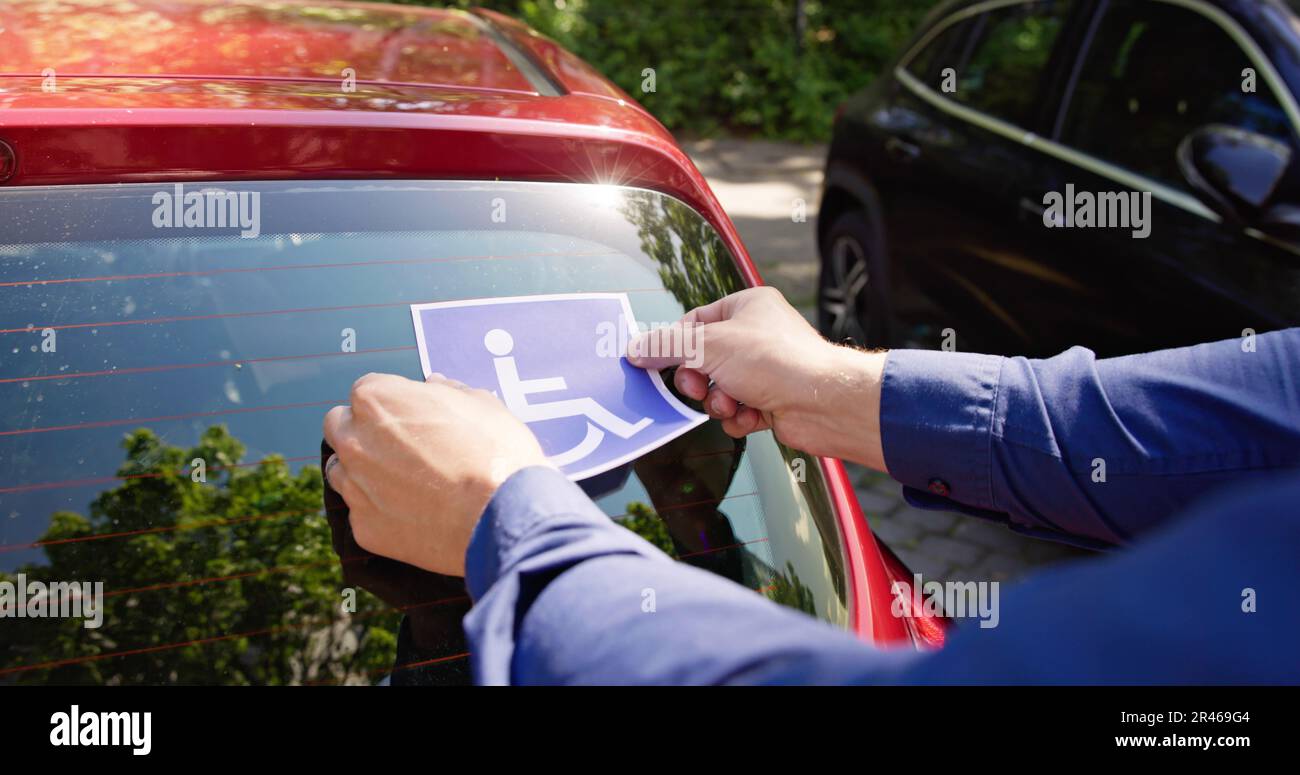 Driver Putting Wheelchair Sticker Sign On Car Vehicle Stock Photo - Alamy