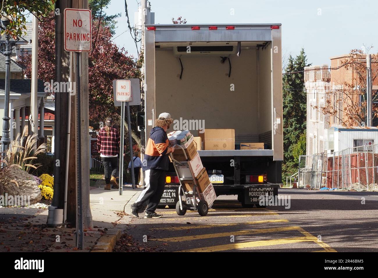Two male movers unloading cardboard boxes from the back of a moving ...