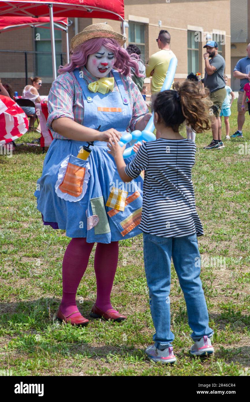Jazzy the clown creates a balloon sword during a carnival celebrating ...