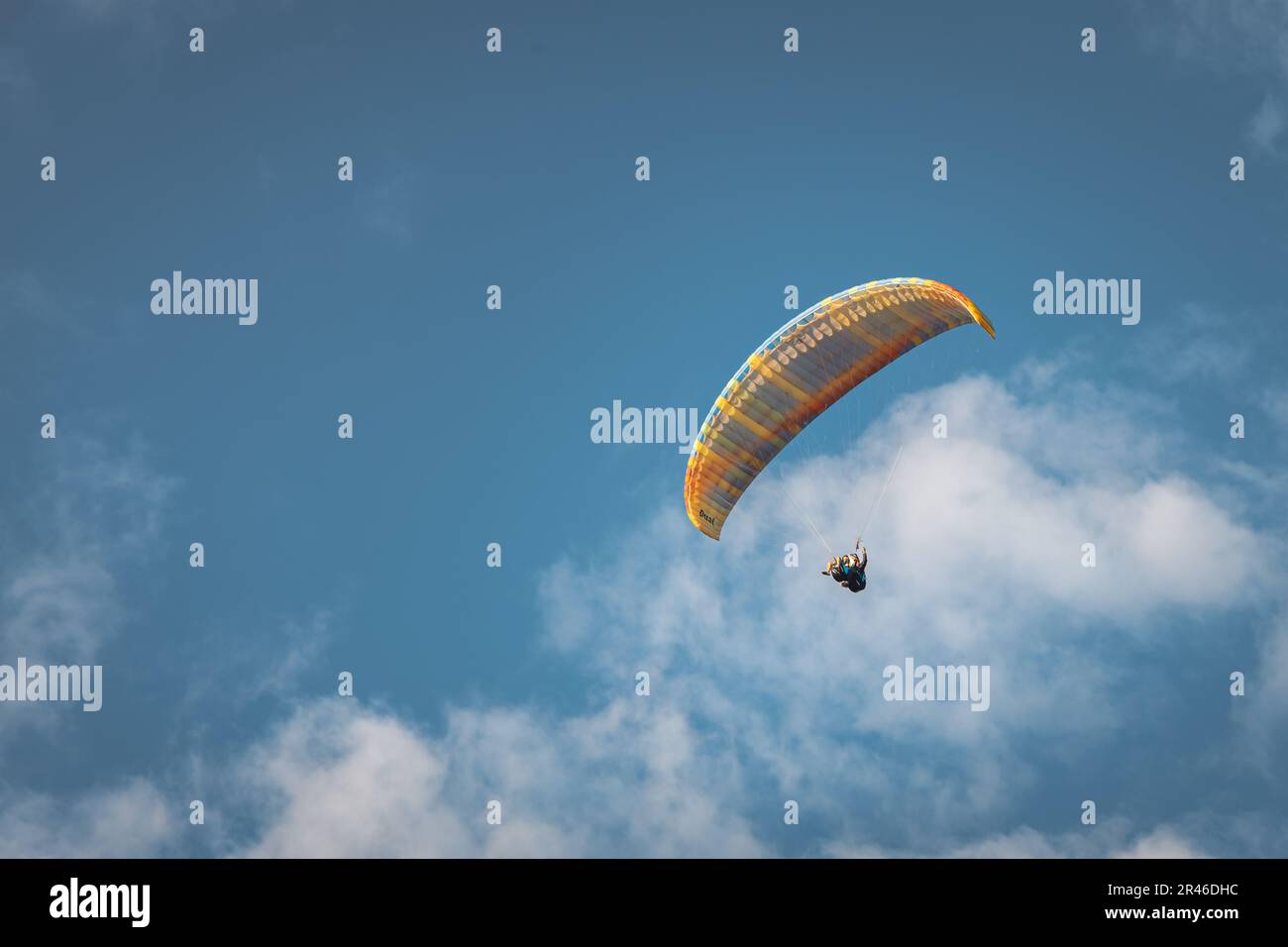 A view of a person gliding through the sky with a parachute, with a ...