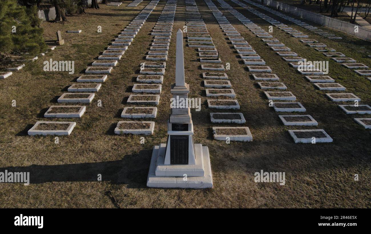 A solemn cemetery with several white graves and a memorial stone ...