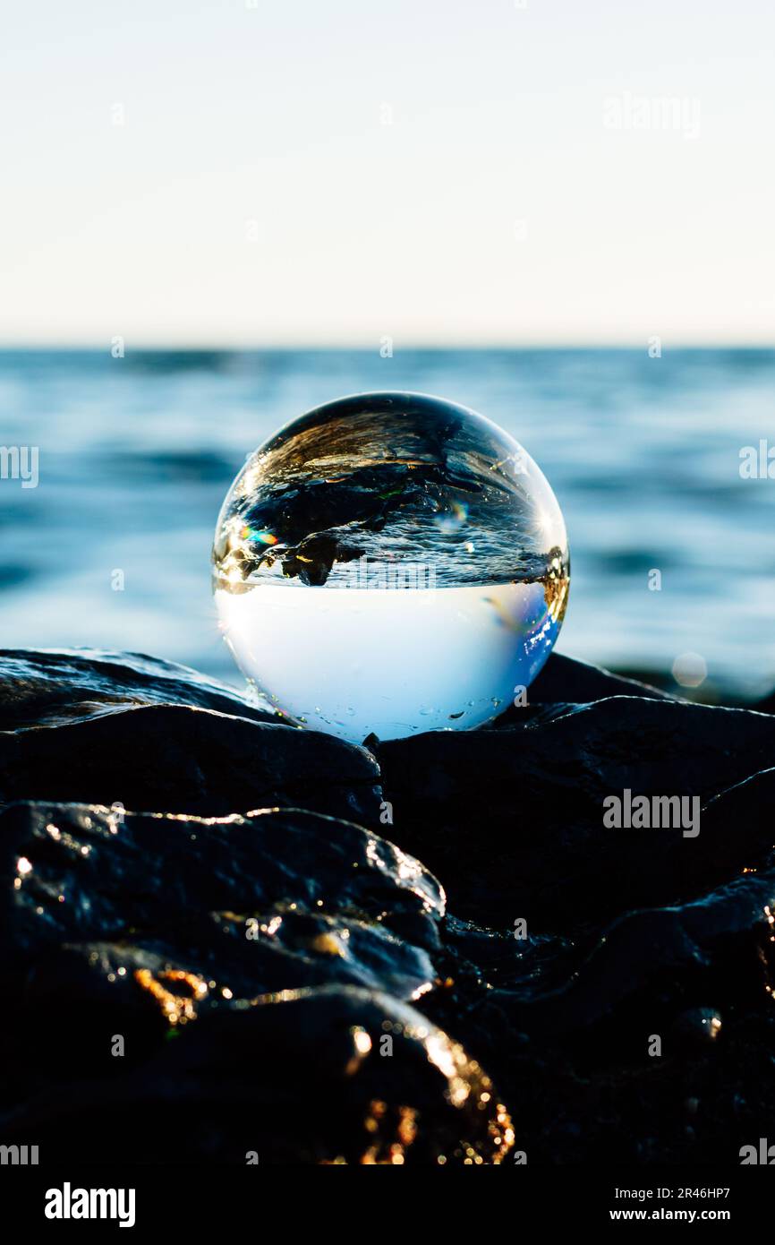 Crystal ball resting on the rocky surface of a beach, View of the beach ...
