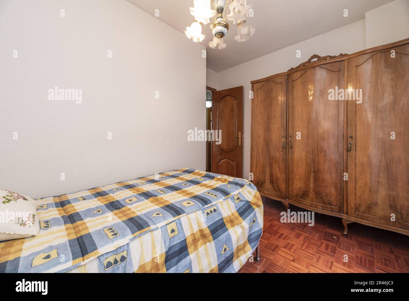 A double bedroom with an anachronistic wooden wardrobe and lamps of the ...