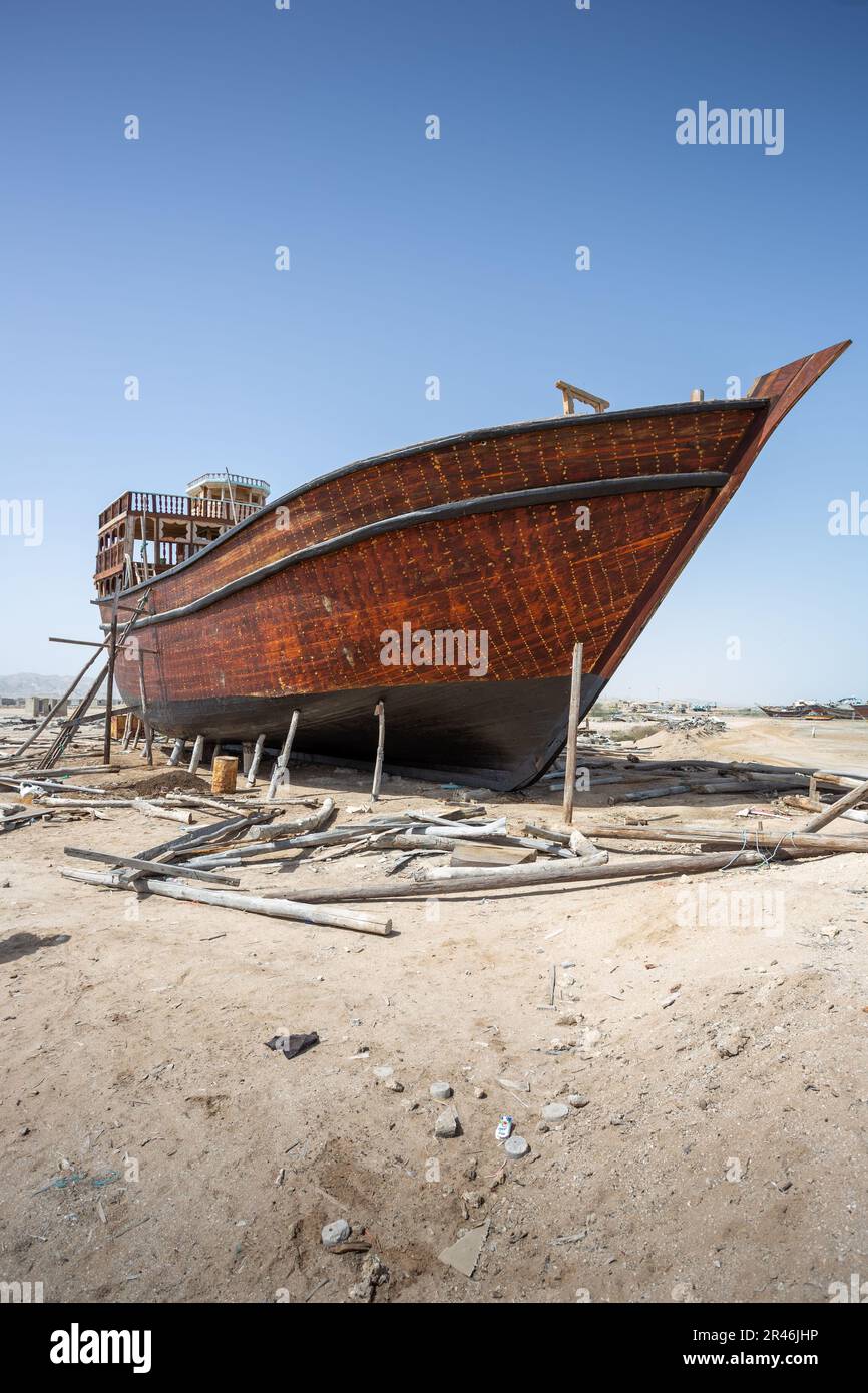 A vintage boat on the sandy shoreline with a rust-covered exterior in ...