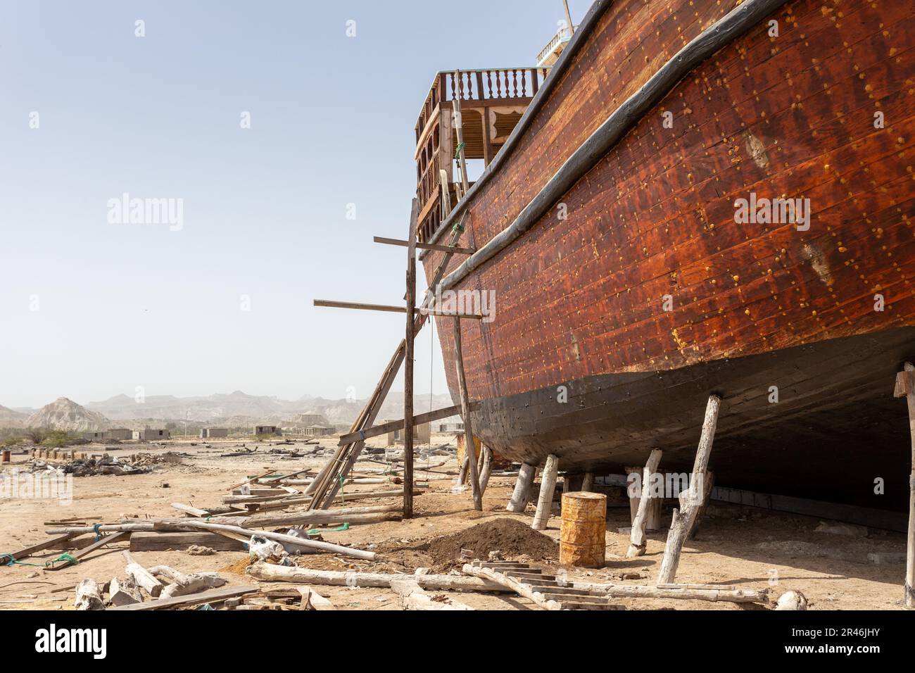 A vintage boat on the sandy shoreline with a rust-covered exterior in ...