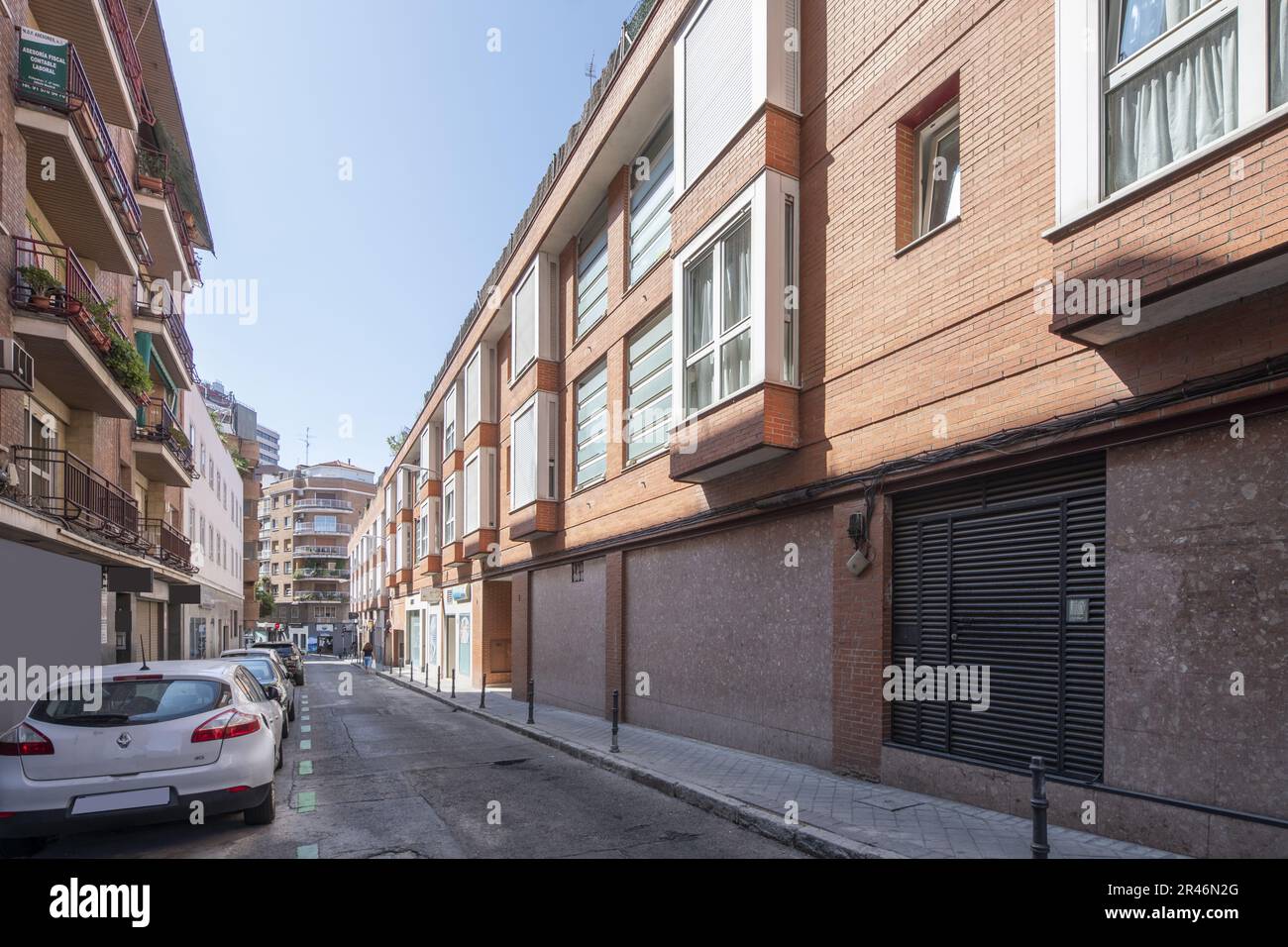 A narrow city street with low-rise buildings on both sides of the ...