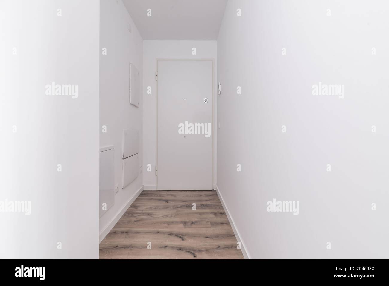 Hallway of a house with white walls and wooden floors and armored ...