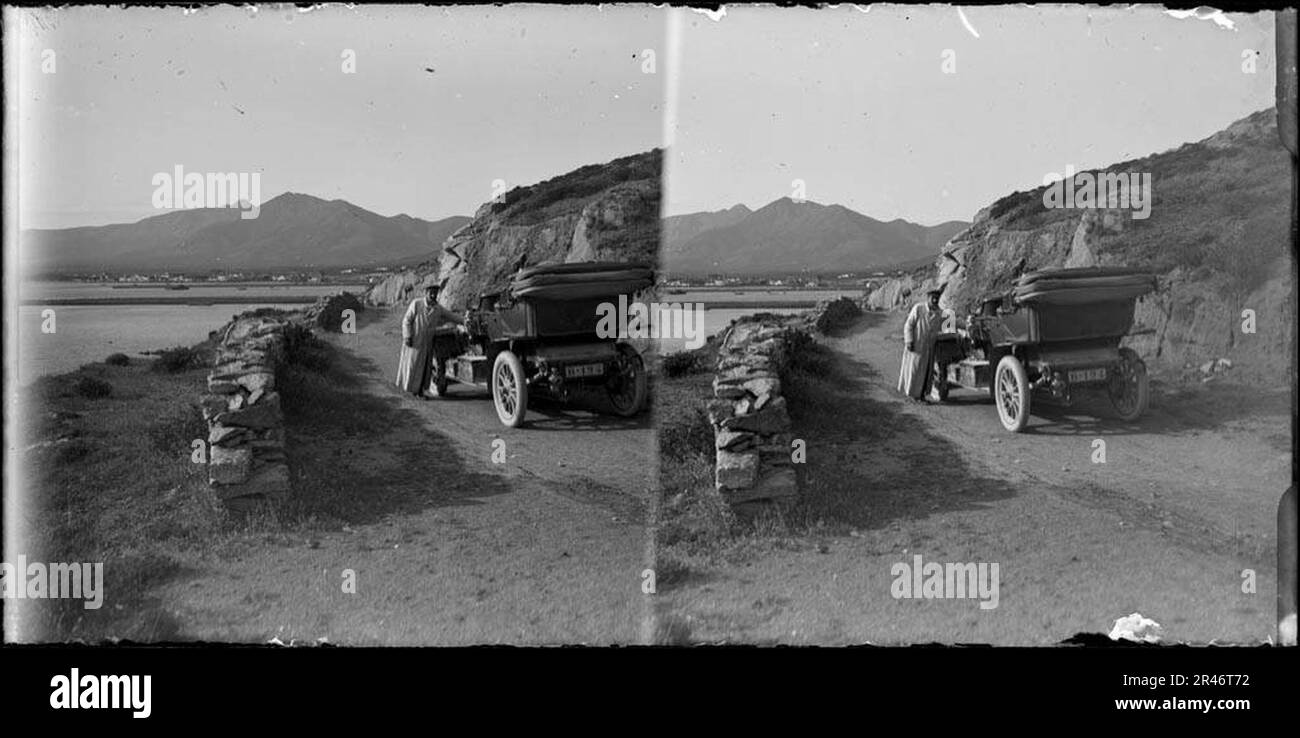 Un home al costat d'un cotxe en una carretera a la vora de la badia de ...