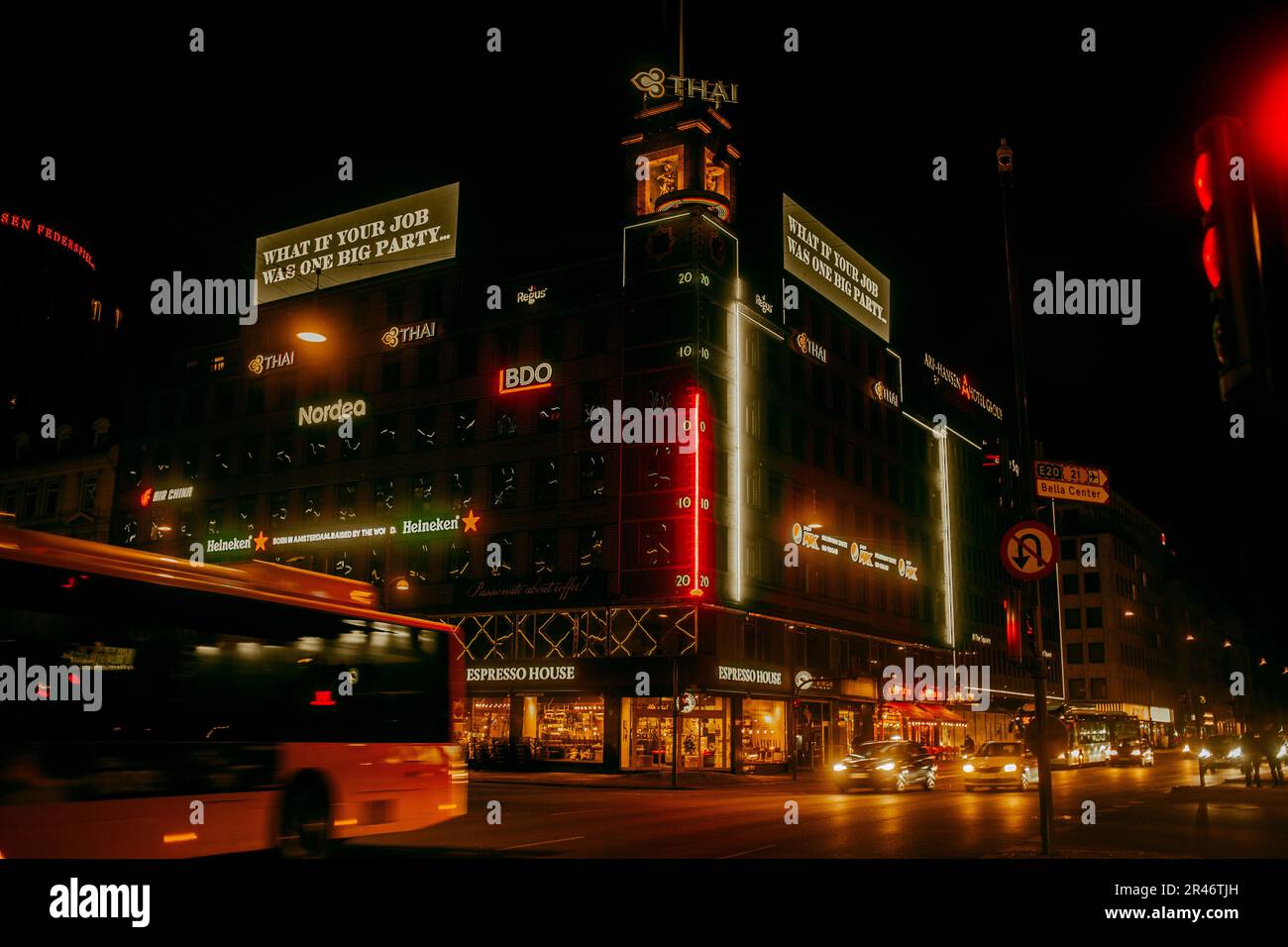 A brightly lit building at night with traffic in the street in ...
