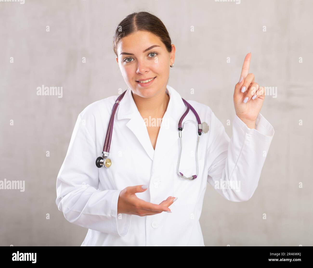 Female doctor in white coat smiling to camera while presenting with ...