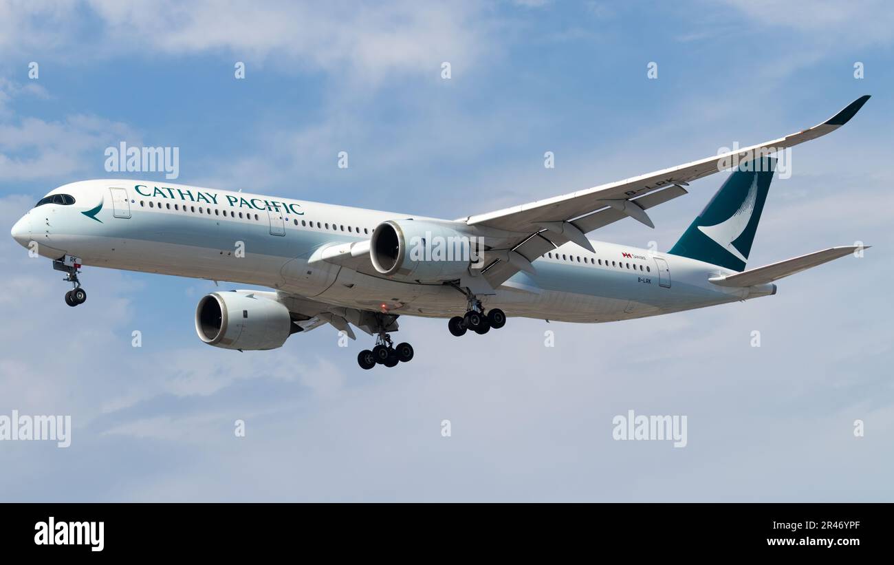 A Cathay Pacific Airlines aircraft soaring against a blue sky backdrop ...