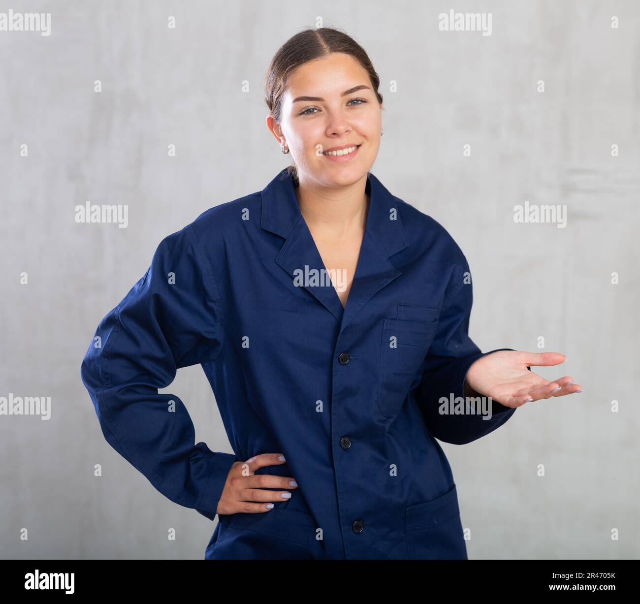 Portrait of emotional storekeeper woman in uniform on gray background ...