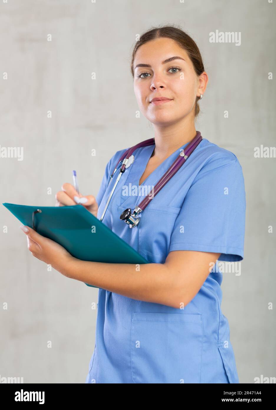 Young happy female nurse writing in file with papers Stock Photo - Alamy
