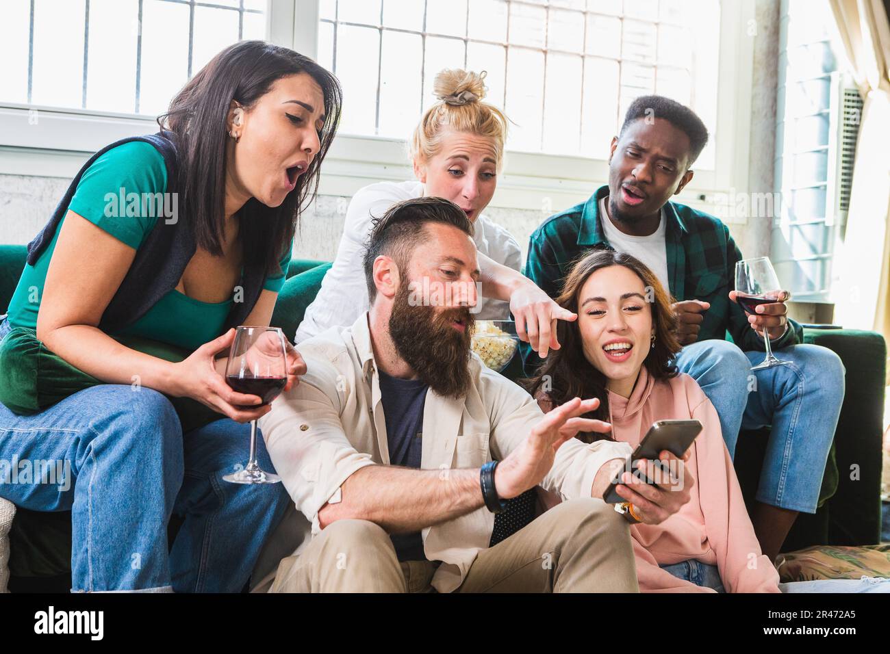 Young friends of mixed nationalities laughing commenting on social ...