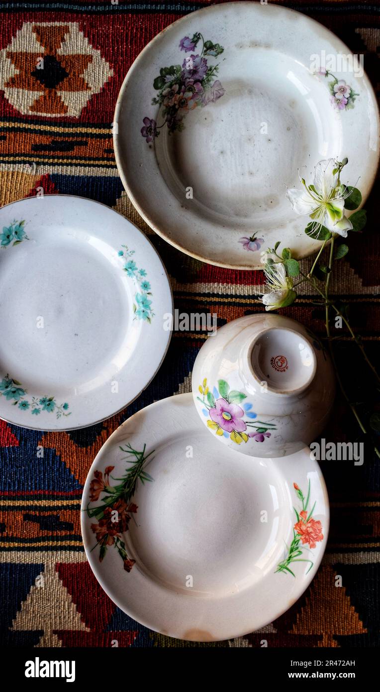 A vertical top-view of a composition of white vintage ceramic plates ...