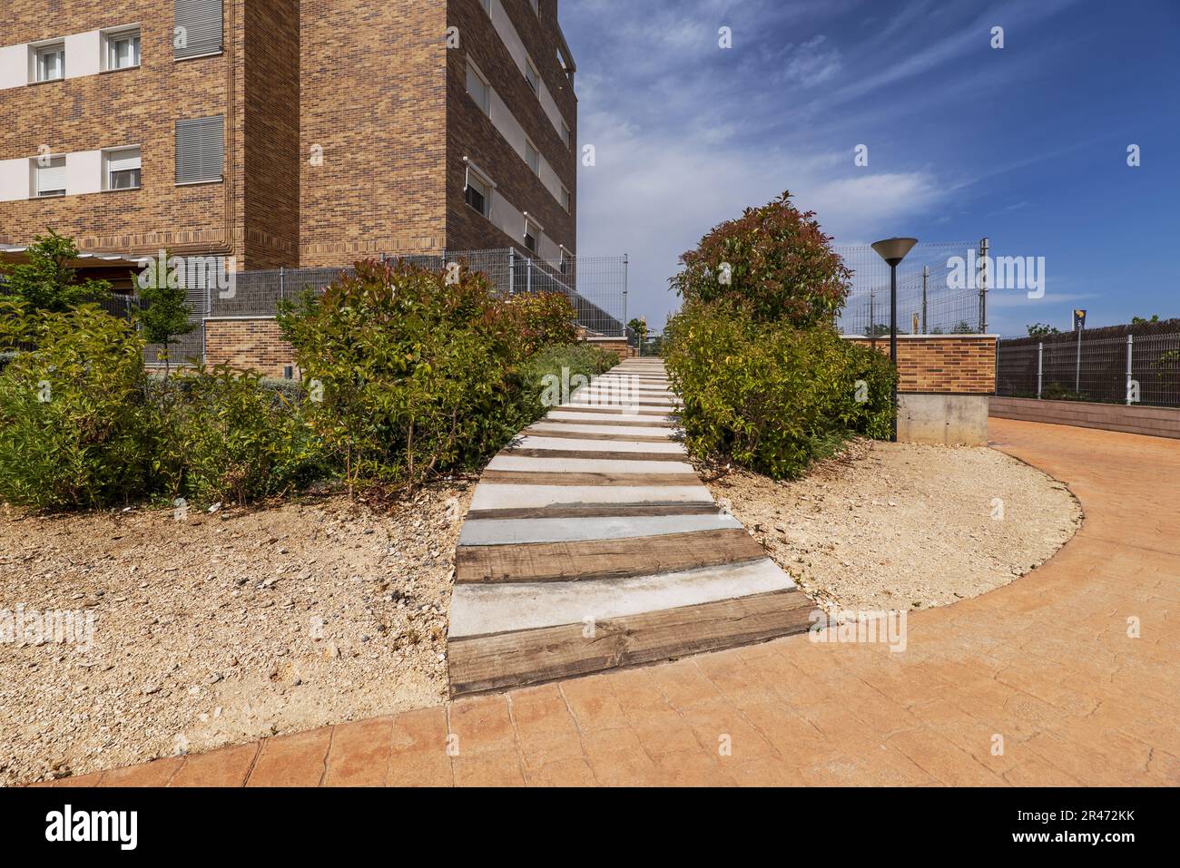 A board and concrete path between hedges leading to the entrance of a ...