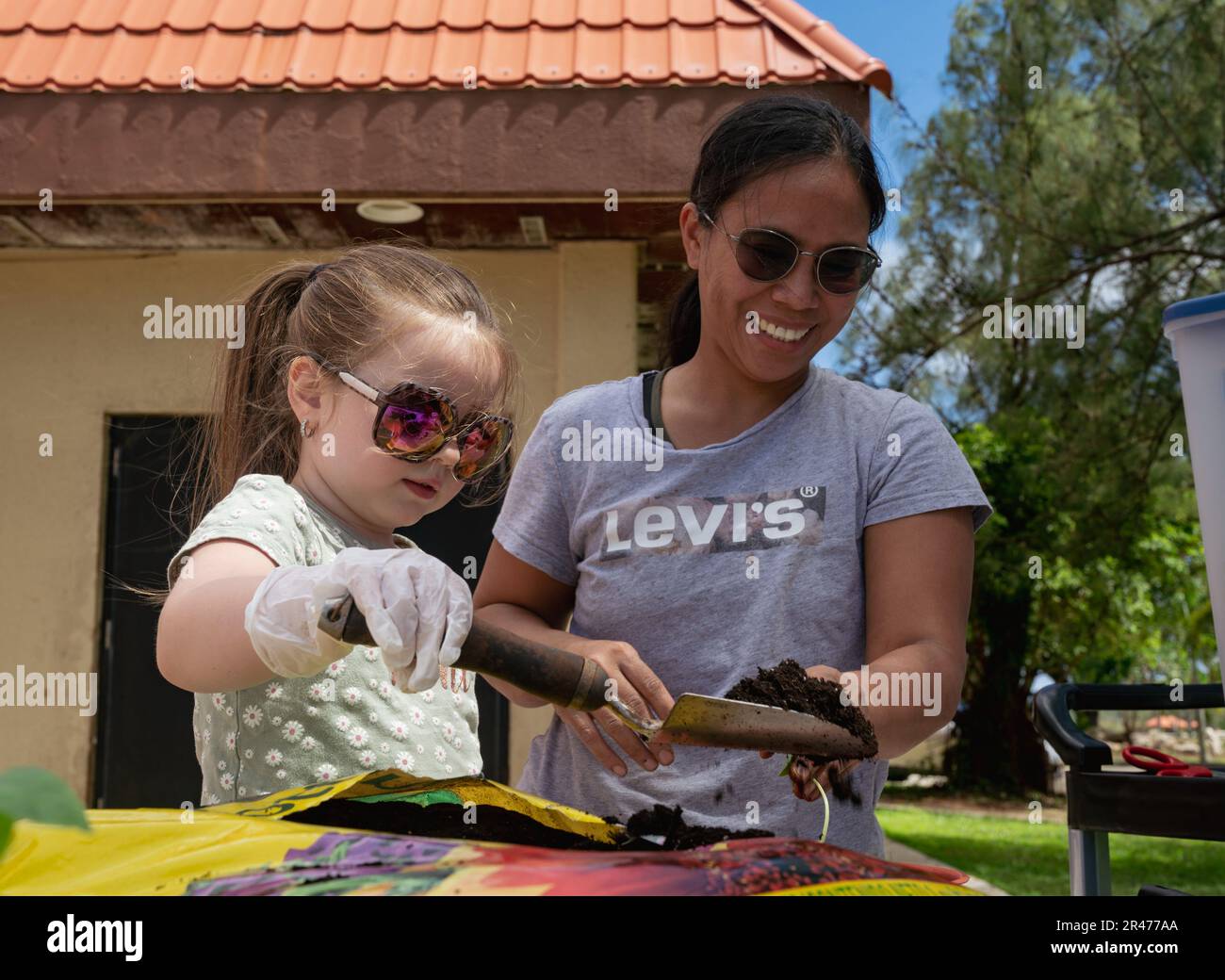 Grace Platt, a USO Andersen Air Force Base volunteer, helps a child pot ...