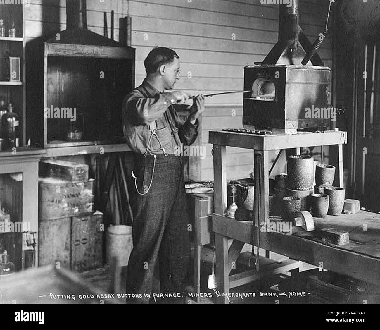 Unidentified man melting gold in a workroom with a furnace and tools ...