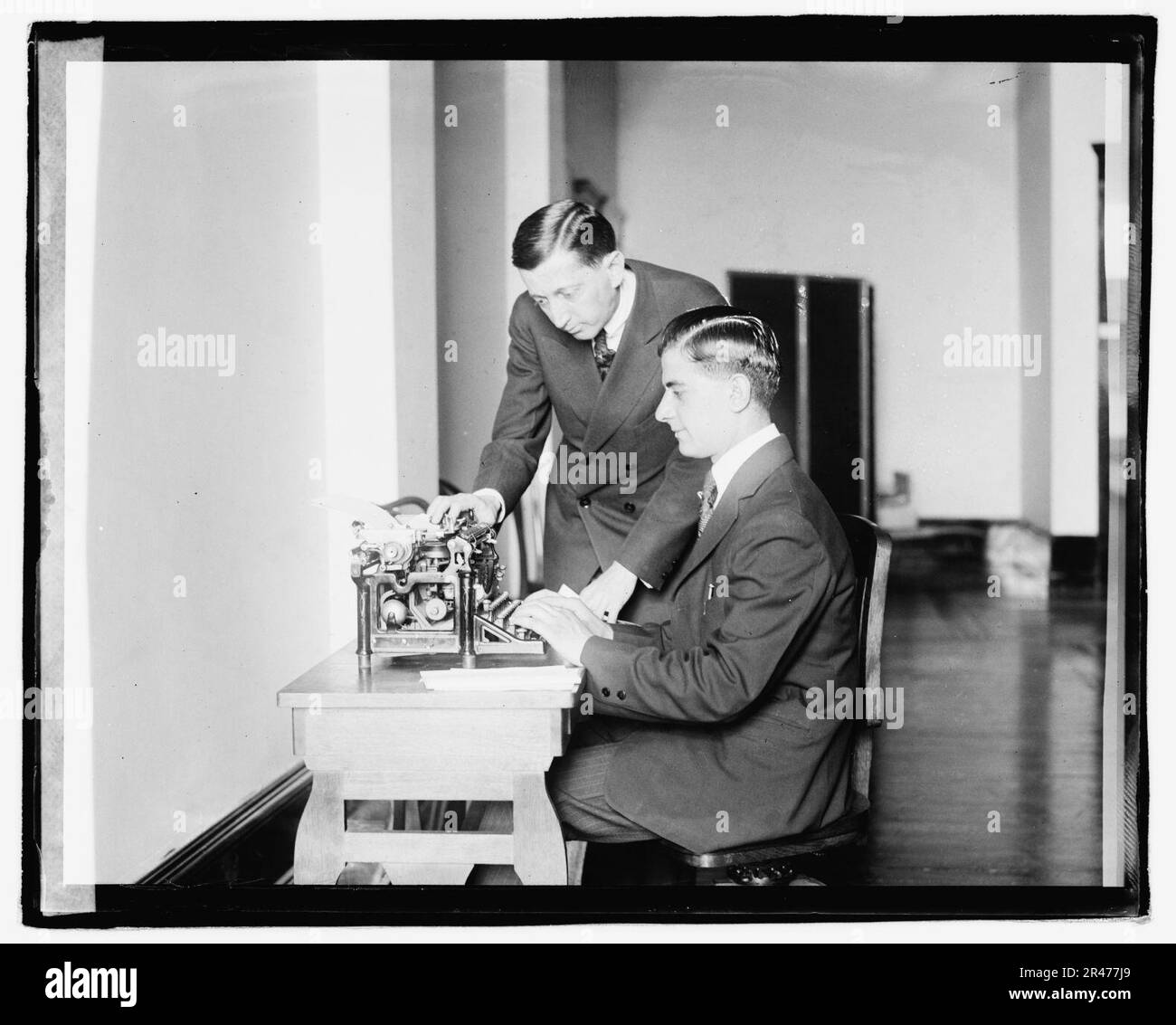 Unidentified men using typing machine Stock Photo - Alamy