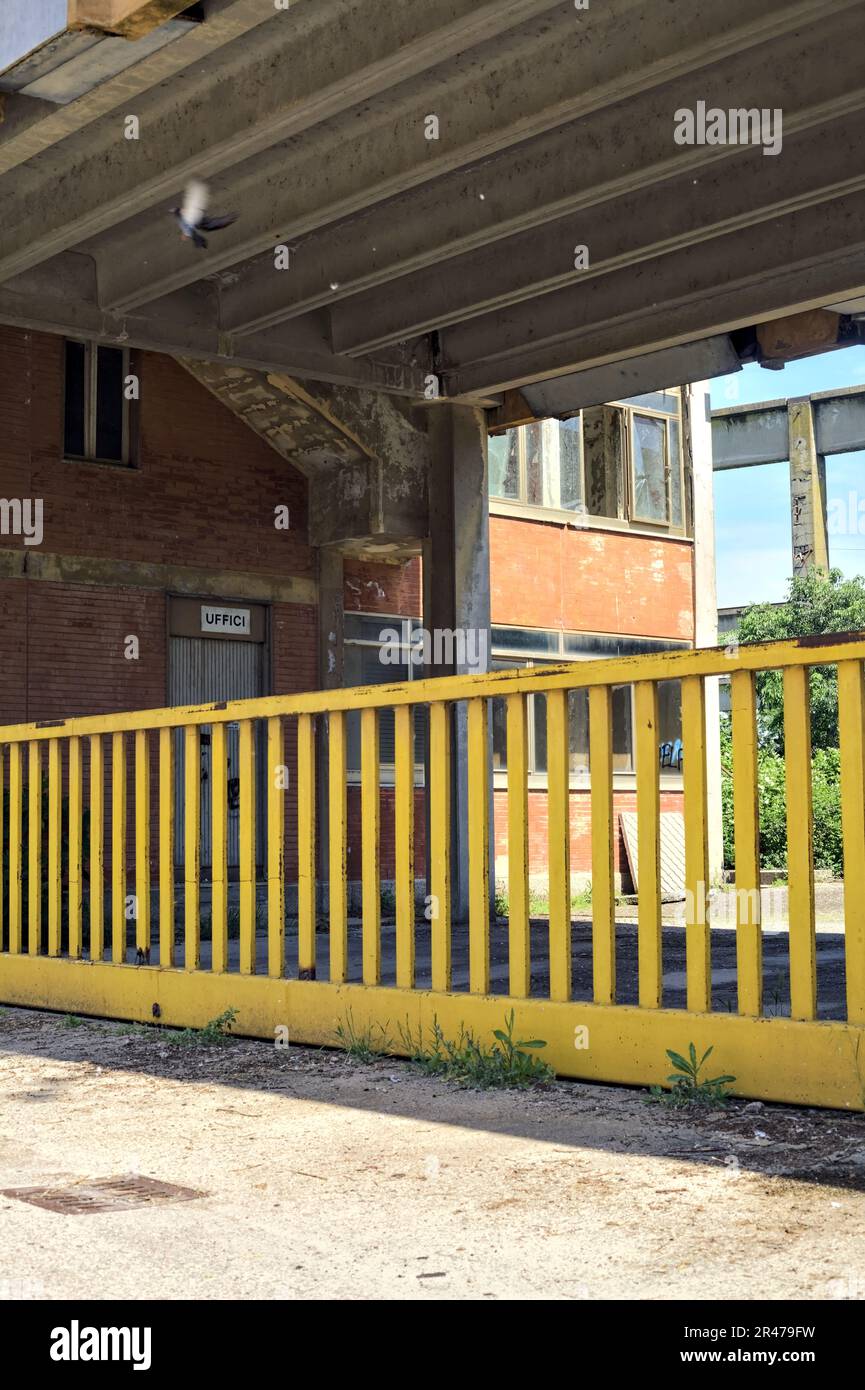 Entrance to an abandoned factory with abundant vegetation blocked by a ...