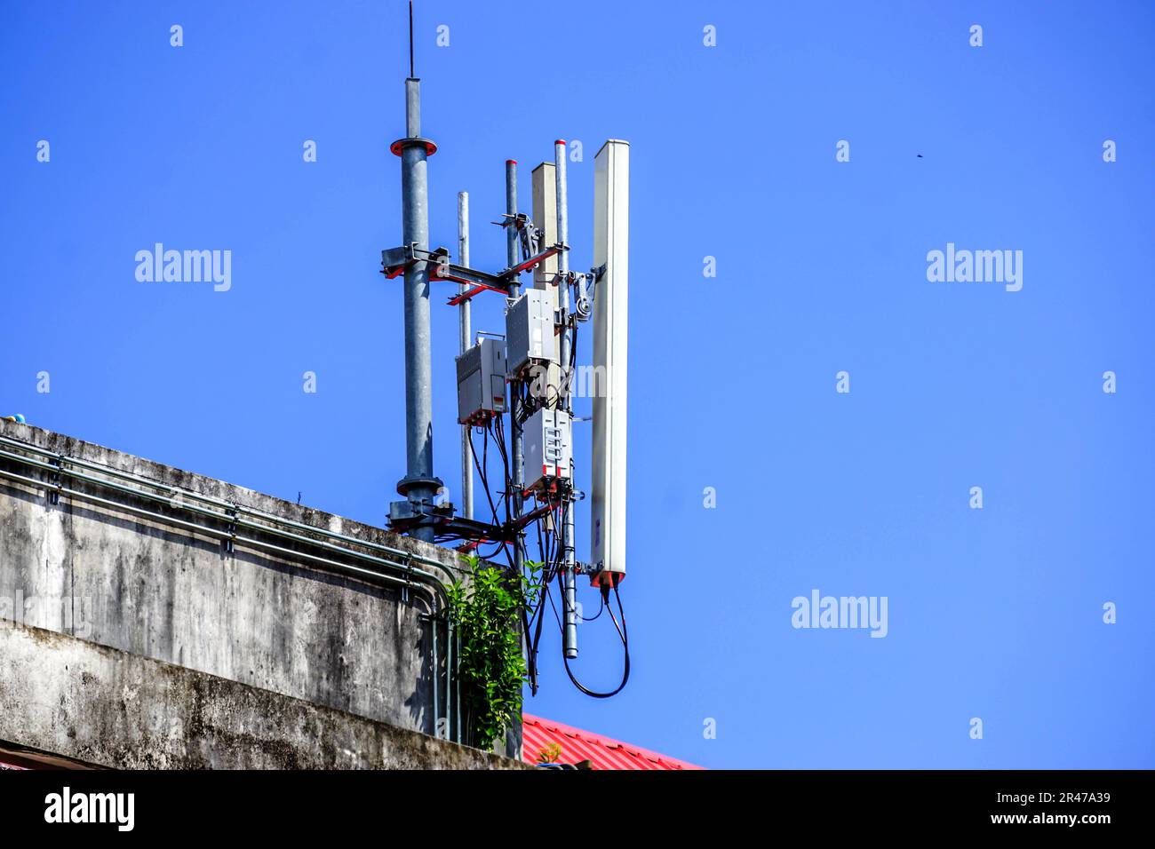Three cellular communication towers on top of a building against a blue ...