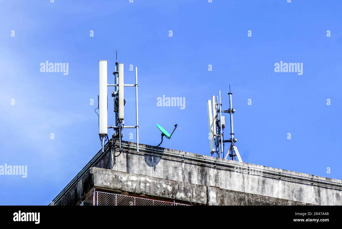 Two television antennas atop a tall commercial building, providing a ...